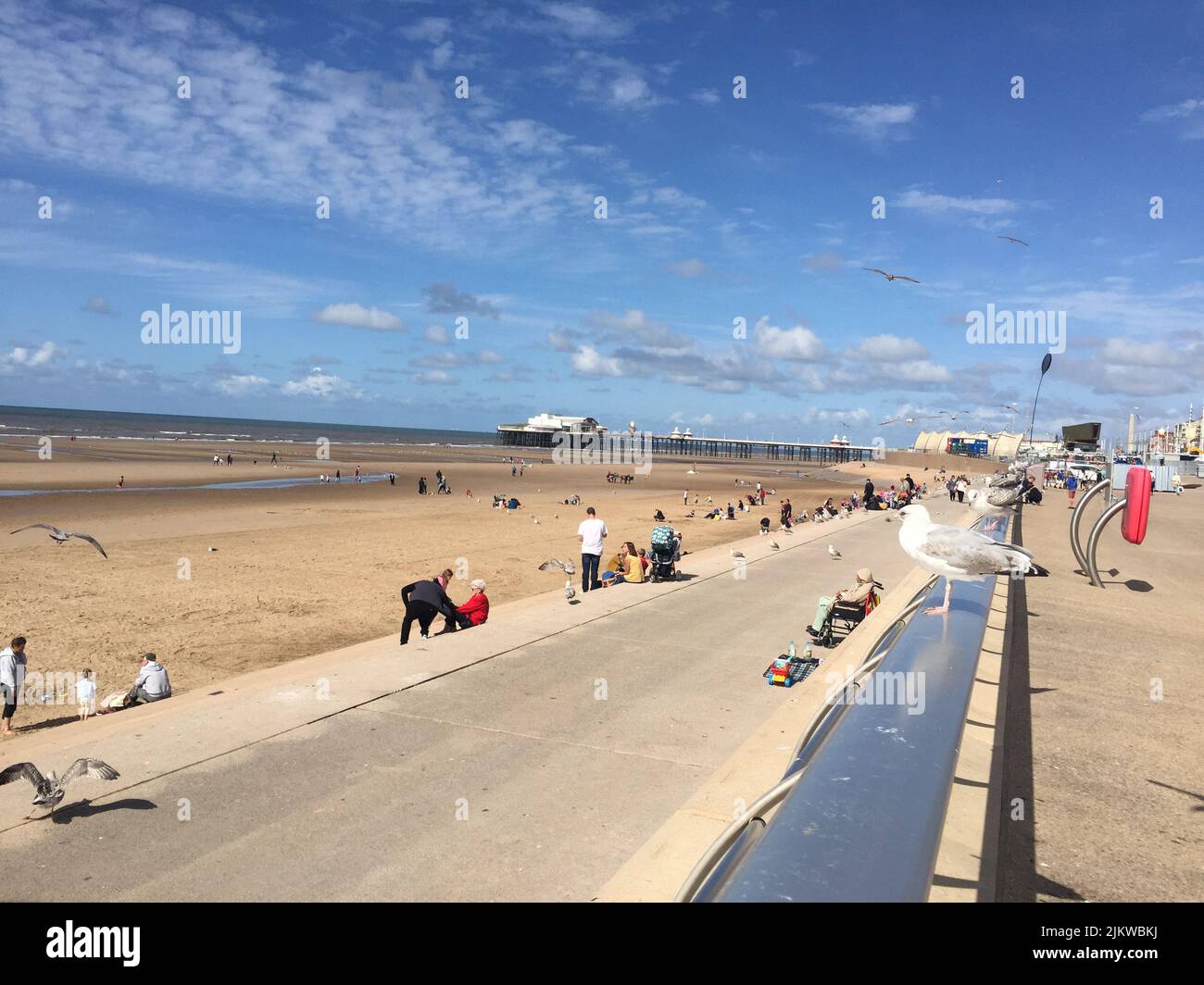The tourists on the Blackpool Beach on blue cloudy sky background in ...