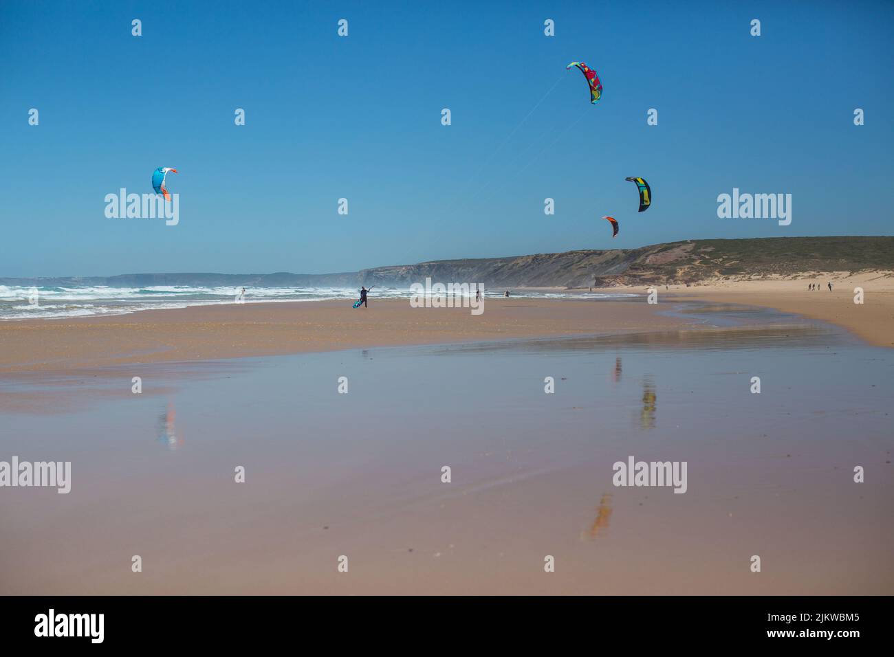 A view of flying kites on sandy wet beach in background of hills in ...