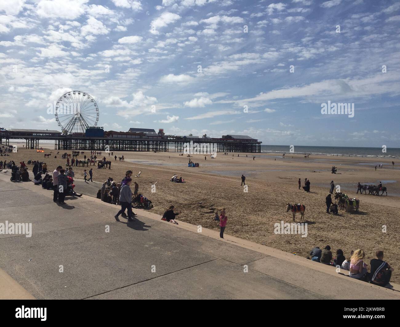 The tourists on the Blackpool Beach on blue cloudy sky background in ...