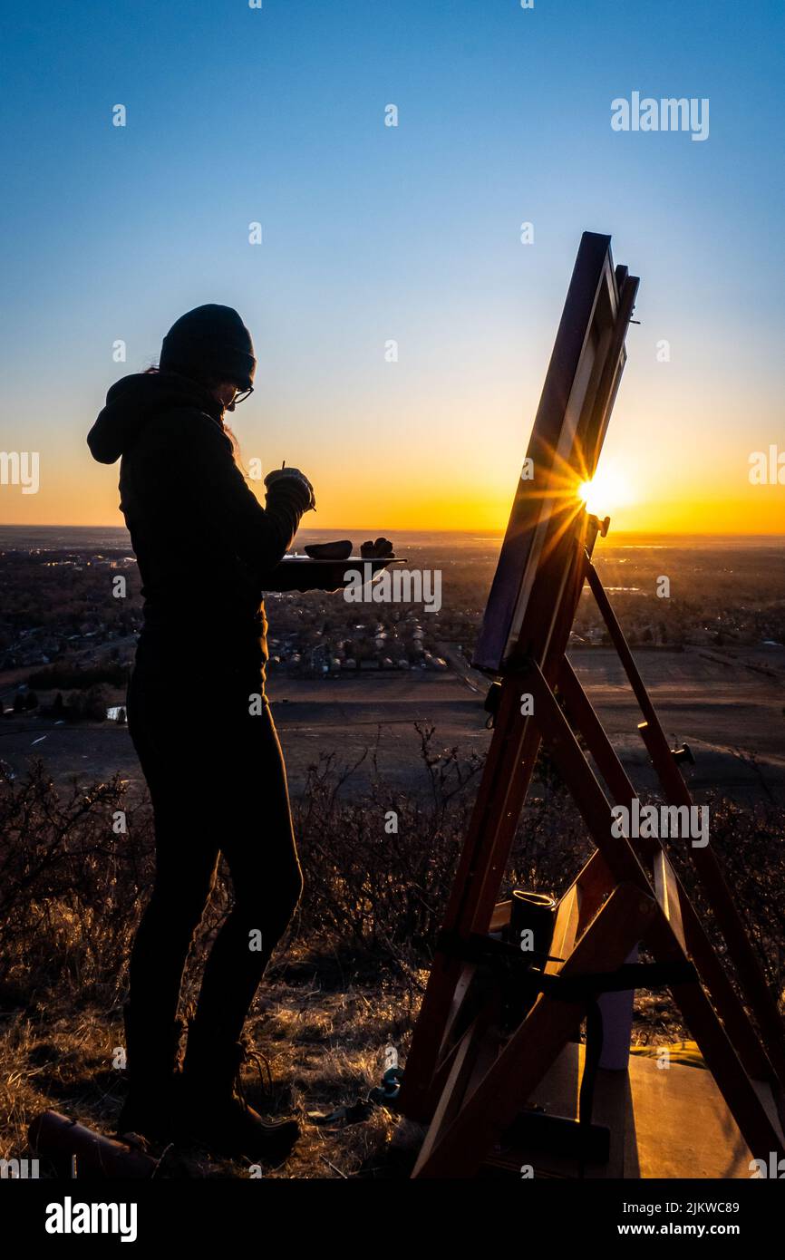 A silhouette of an artist drawing on a high place and looking to the ...