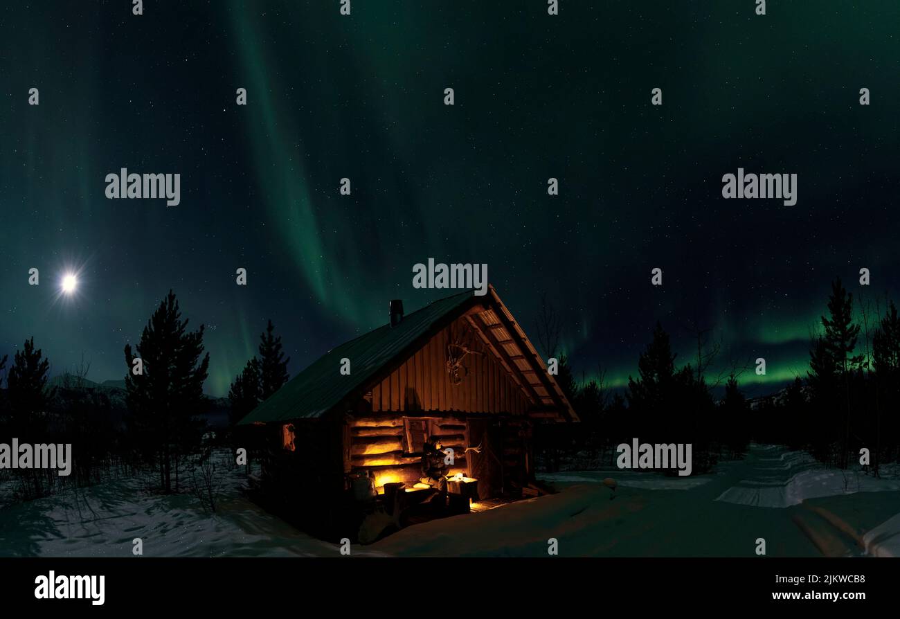 Winter night scene of log cabin with full moon and northern lights ...