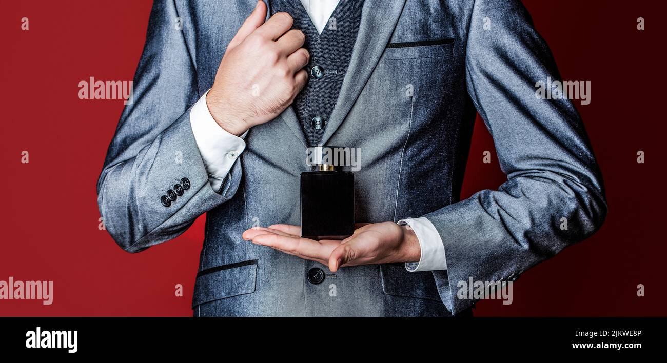 Man holding up bottle of perfume. Men perfume in the hand on suit ...