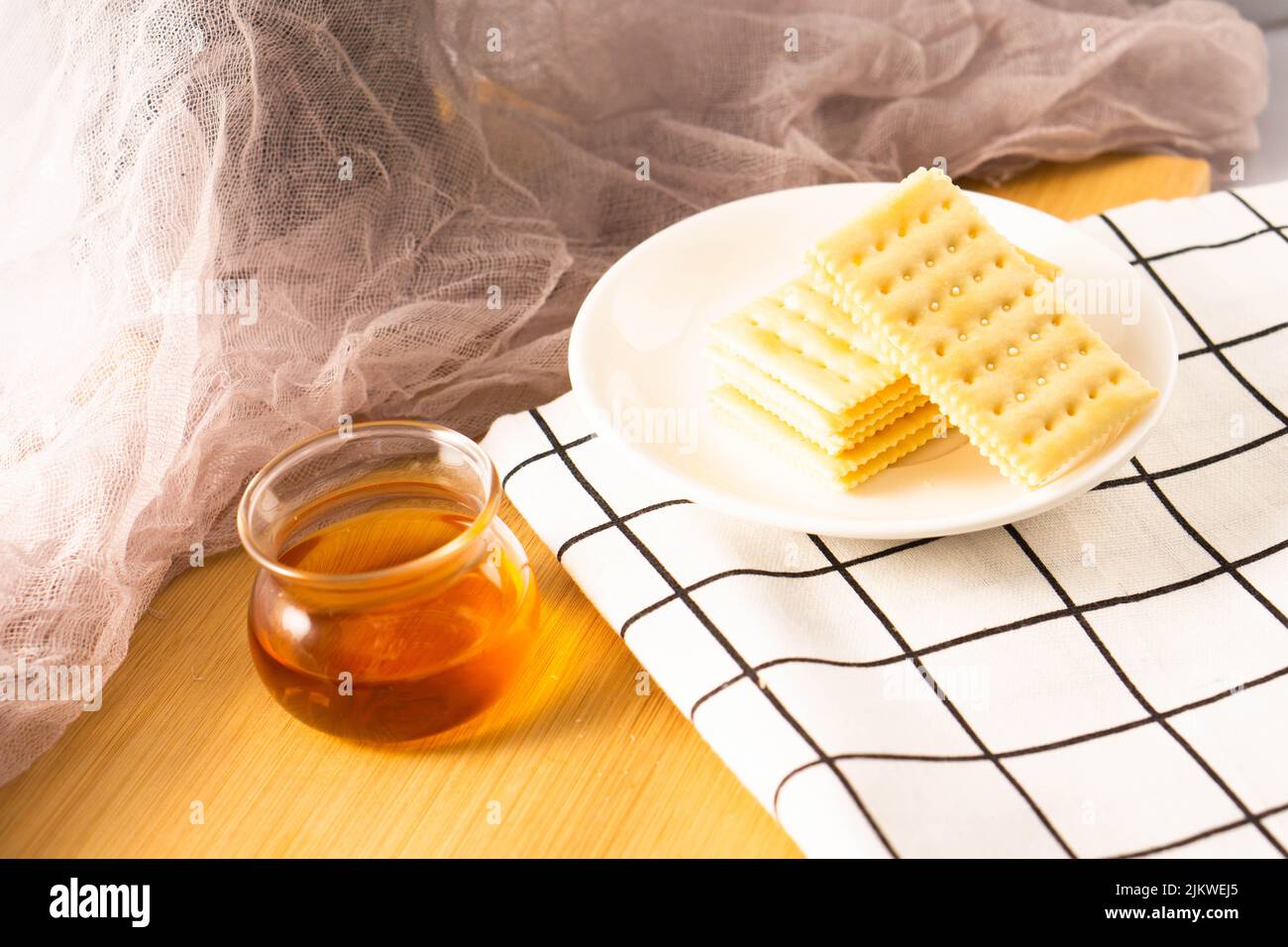 A closeup of crispy crackers on the white plate and a transparent cup ...