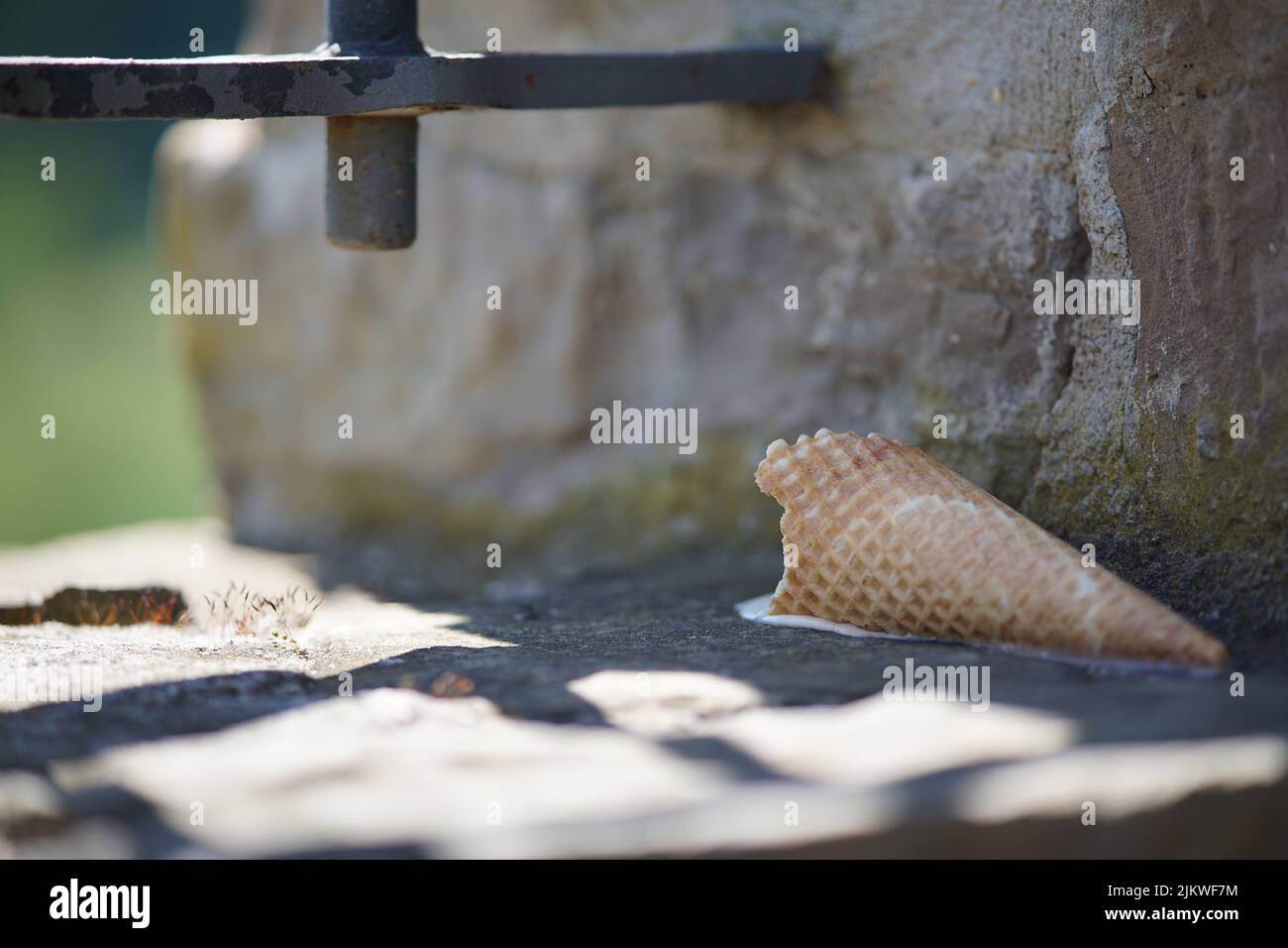 A selective focus shot of ice cream cone on the concrete ground on a ...