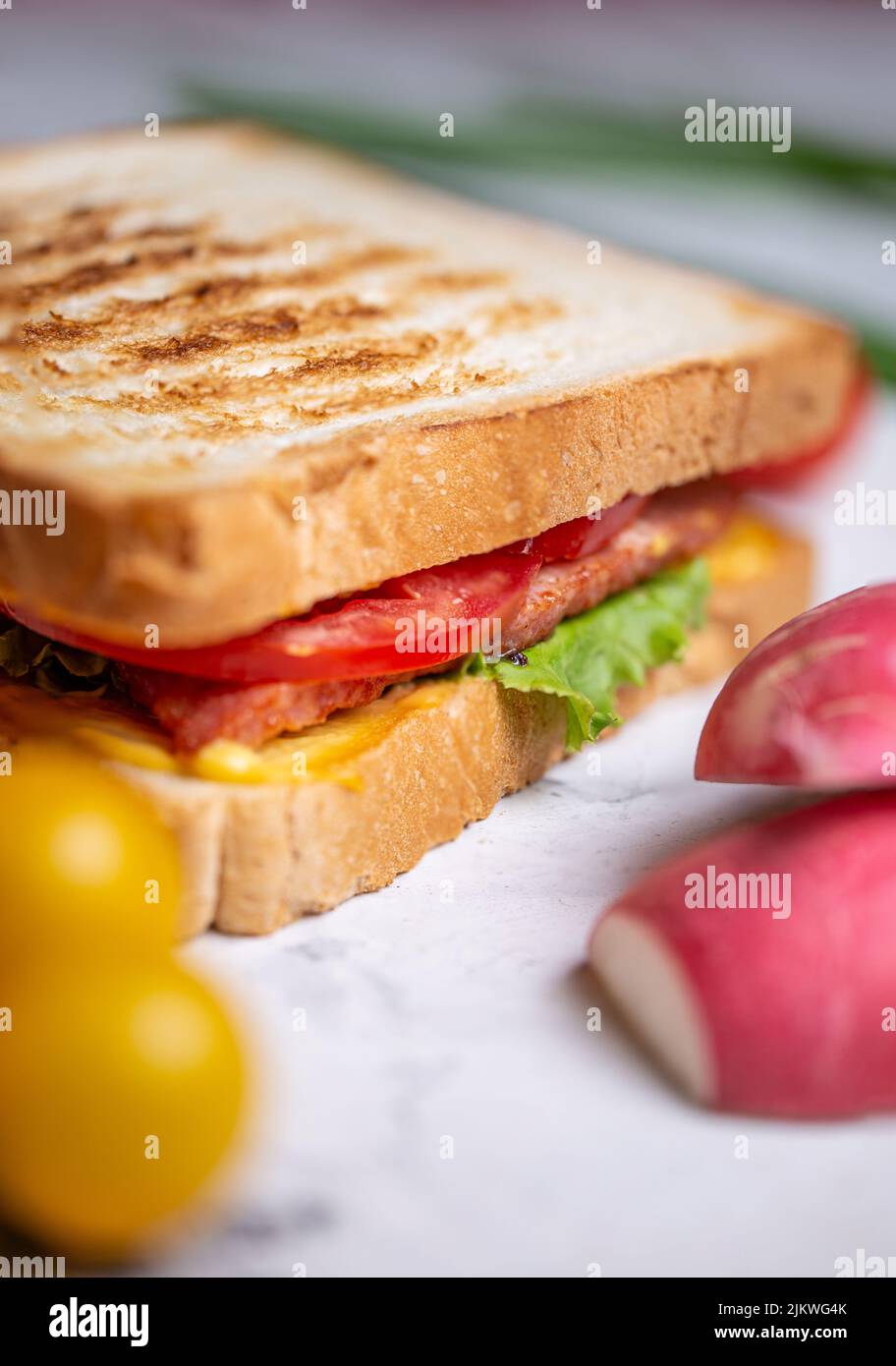 sandwich of two bread toasts with stuffing and vegetables on a wooden ...