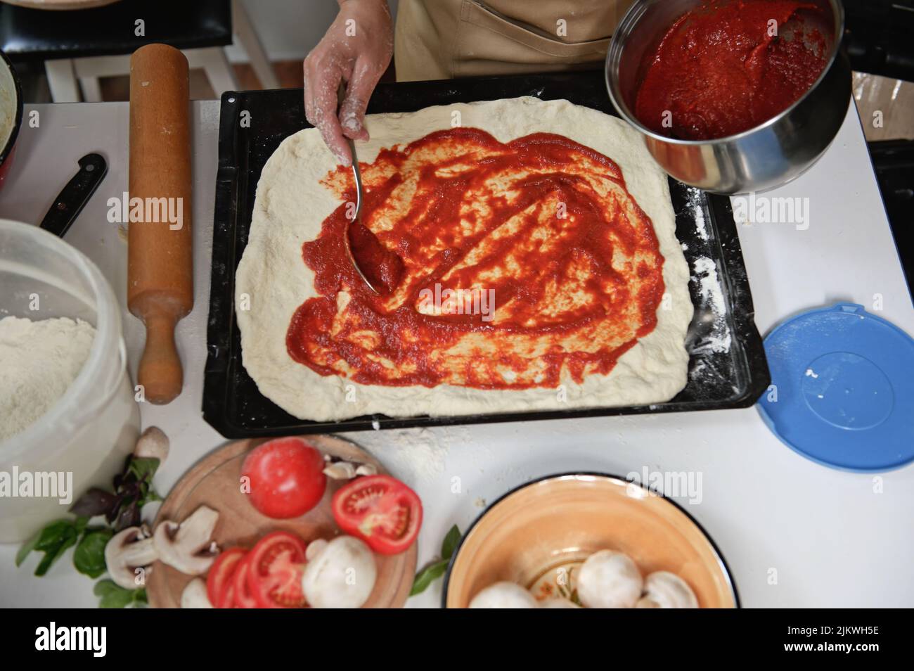Top view. Process of preparing pizza. Chef pours tomato sauce over the ...