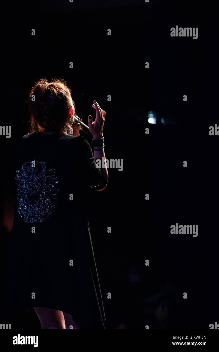 A vertical shot of a woman singing on the stage with black background ...