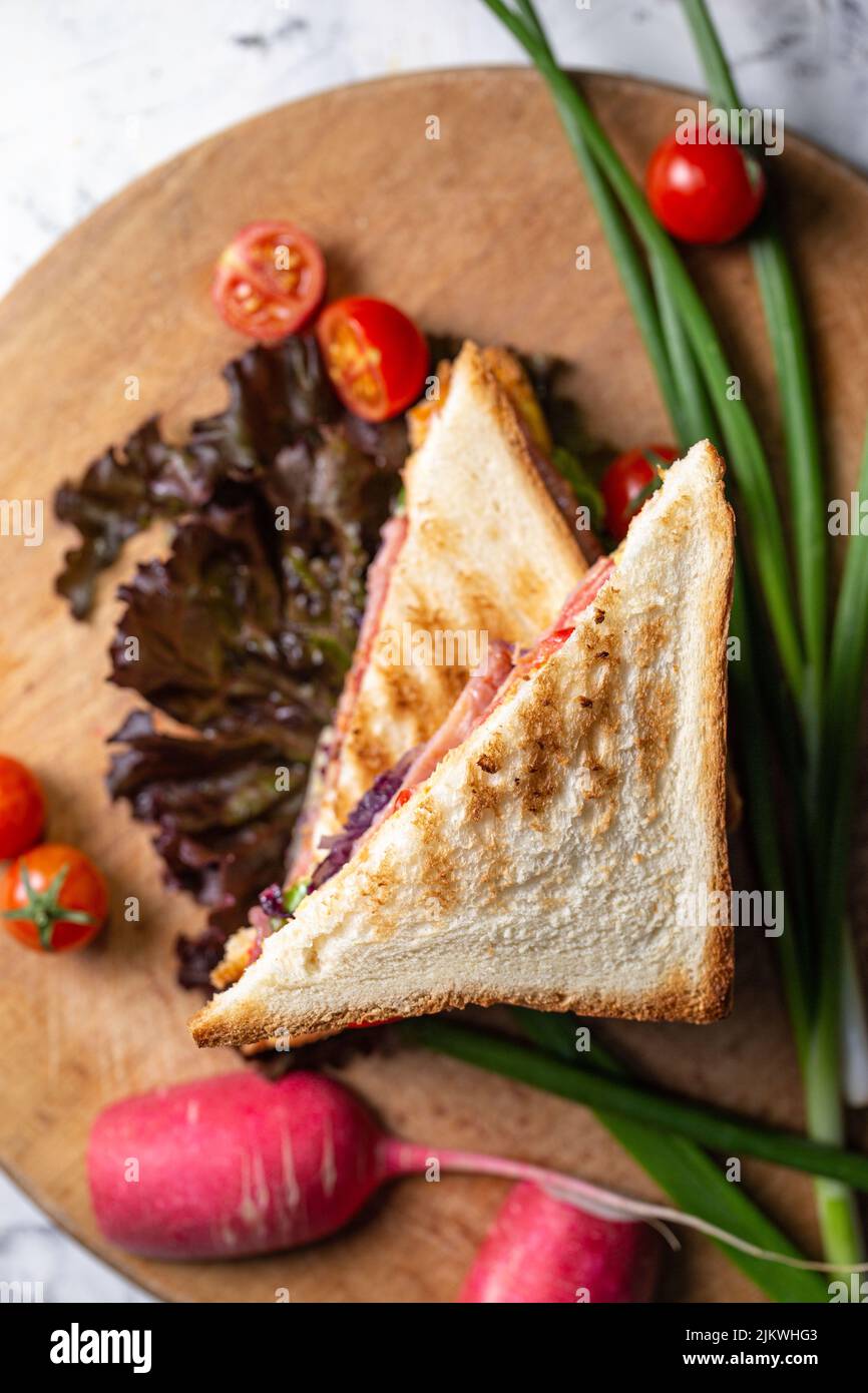 sandwich of two bread toasts with stuffing and vegetables on a wooden ...