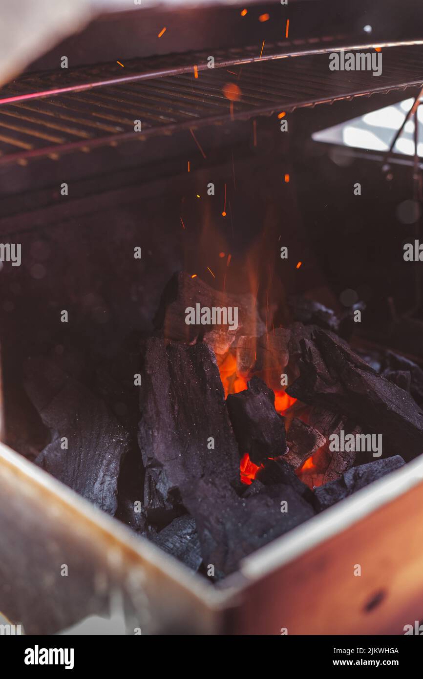A vertical closeup of the glowing campfire with charcoal and burnt wood ...