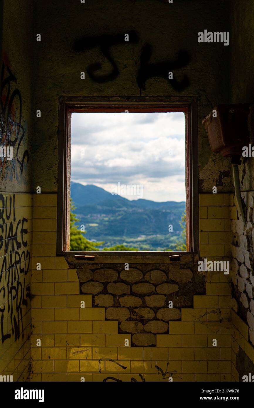 A vertical closeup of an open square shape window on an old stone ...