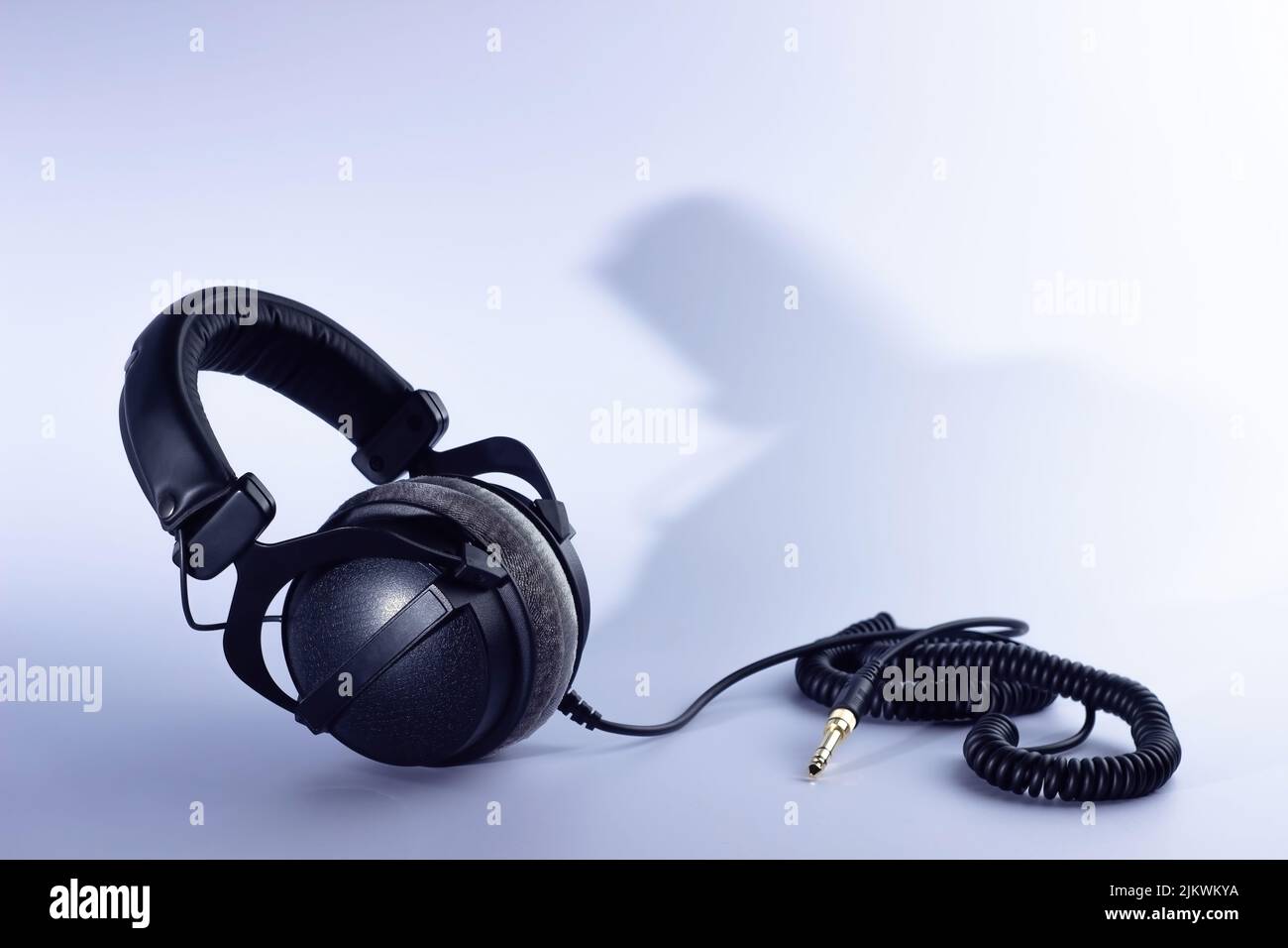 Closed-back studio headphones with a coiled cable stand sideways on a ...