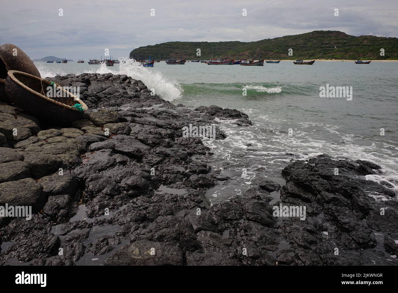 A Vietnamese round fishing boat on the coast of the sea with a port ...