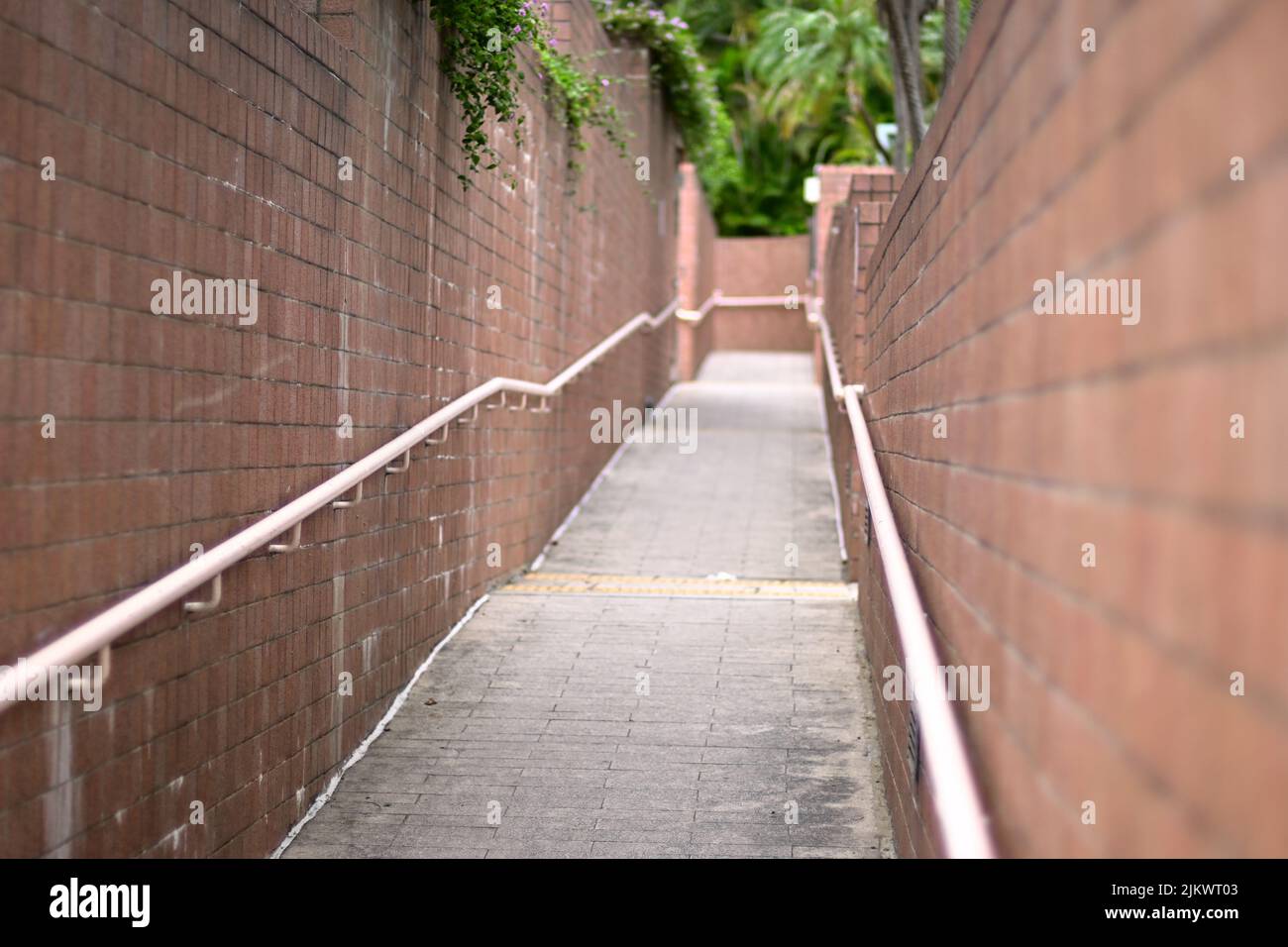 A sloped alley between brick walls with handrails at a park in Hong ...