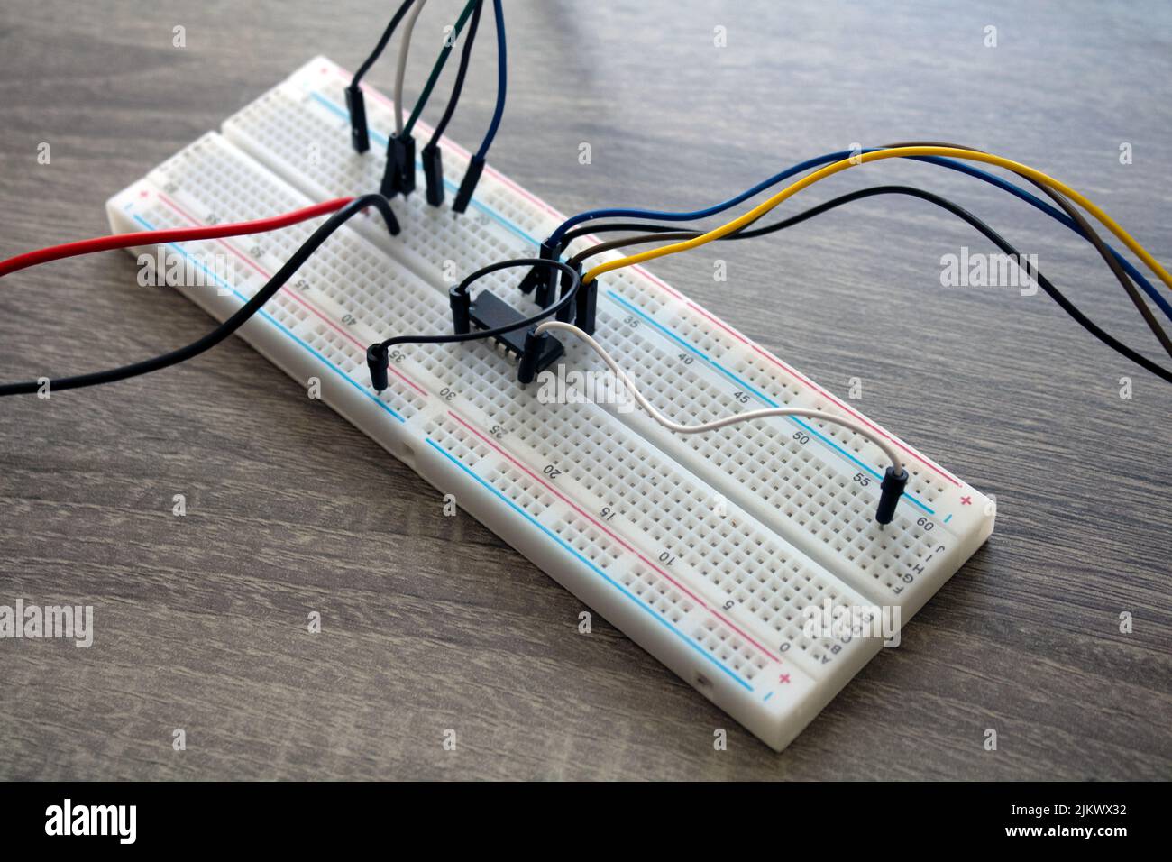 micro chip and wires on breadboard for electrical engineering on wooden ...