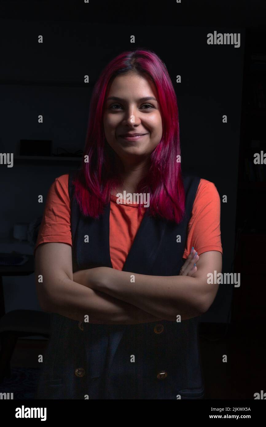 A vertical shot of a Hispanic woman with bright pink hair, smiling at ...