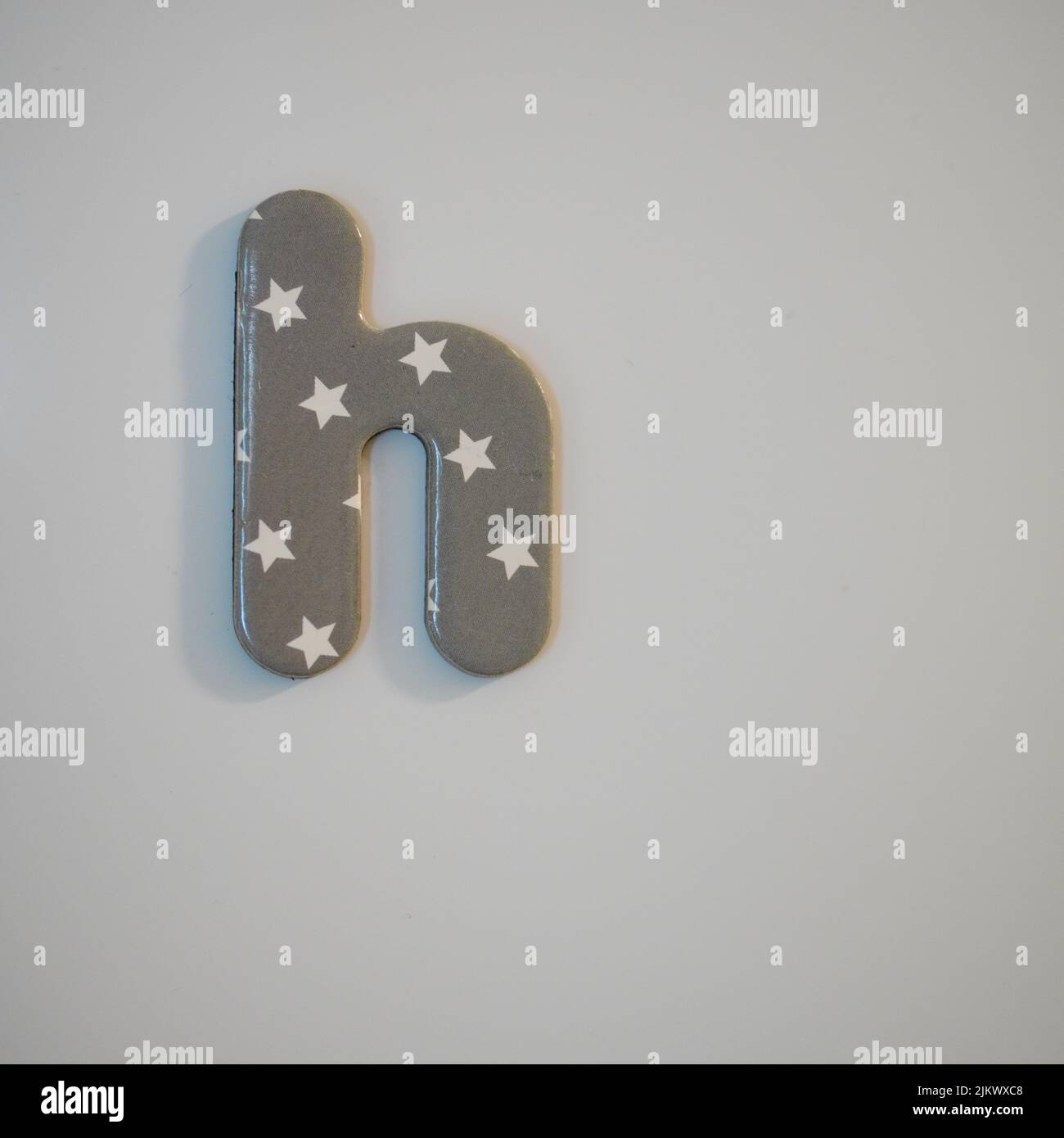 A cardboard lowercase letter "h" with asterisks on a gray background ...