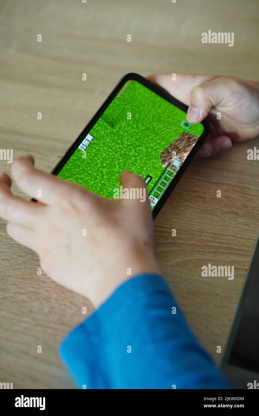 A kid playing Minecraft on a smartphone by a table Stock Photo - Alamy