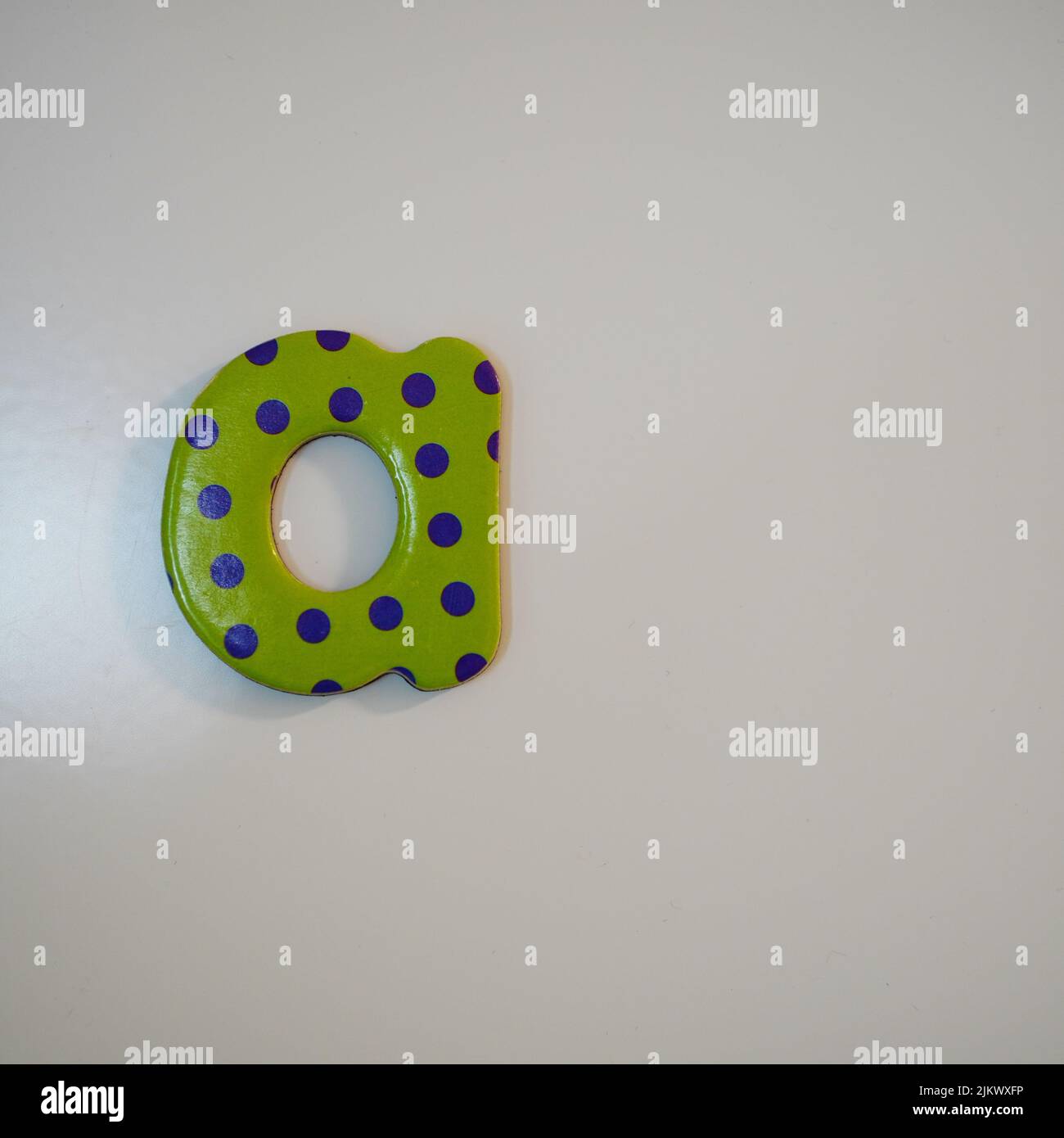 A cardboard lowercase letter "a" with polka dot pattern on a gray ...