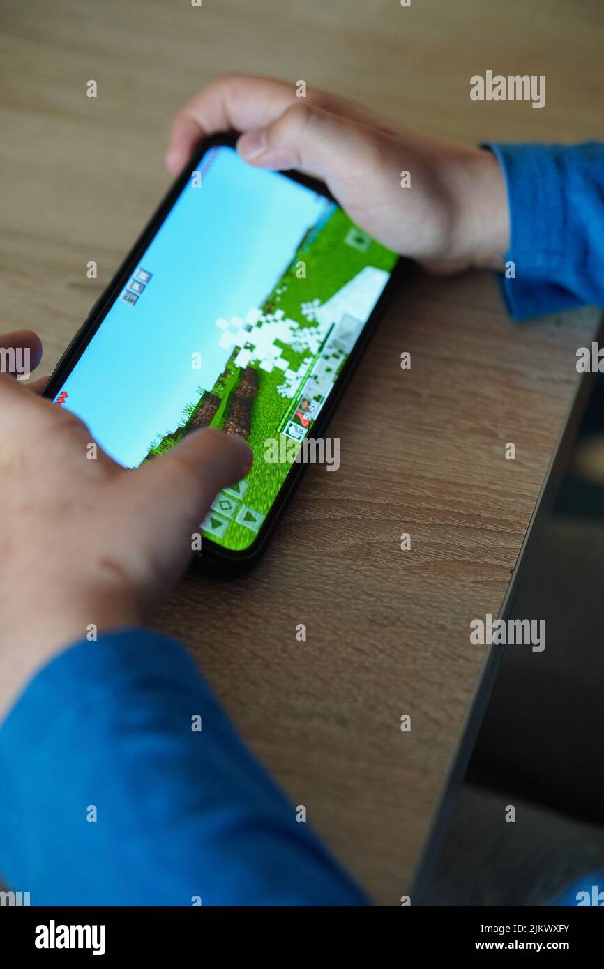 A kid playing Minecraft on a smartphone by a table Stock Photo - Alamy