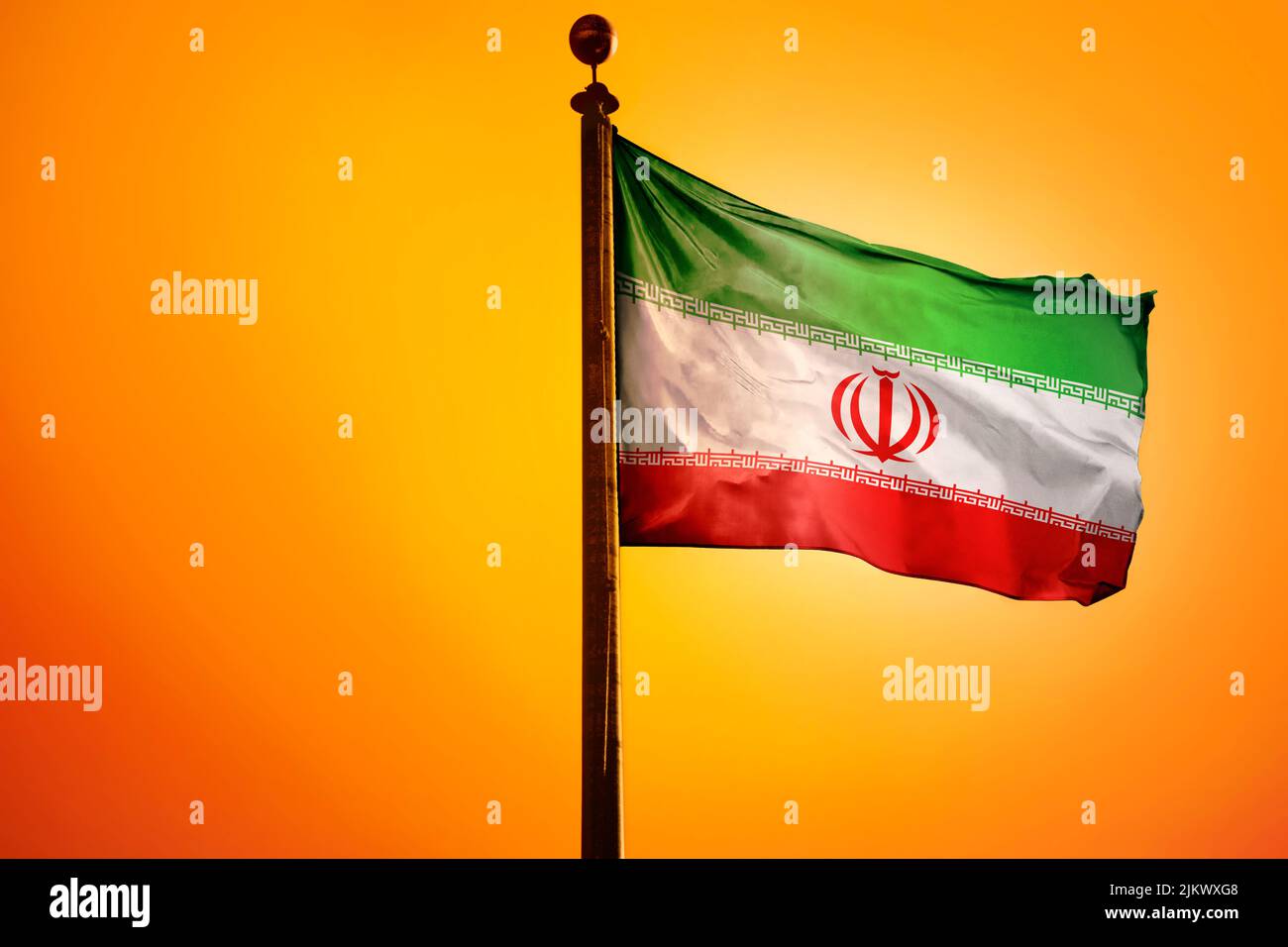 The national flag of Iran on a flagpole isolated on an orange ...