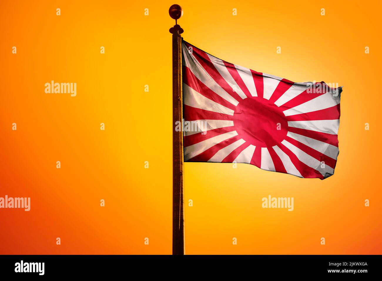 The old flag of Japan on a flagpole isolated on an orange background ...