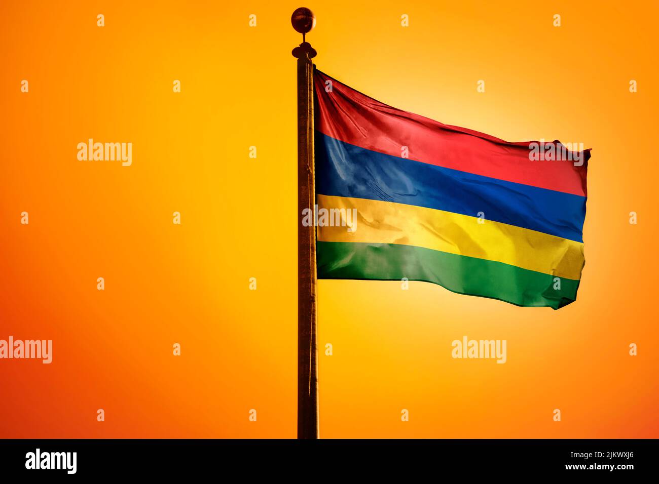 The national flag of Mauritius on a flagpole isolated on an orange ...