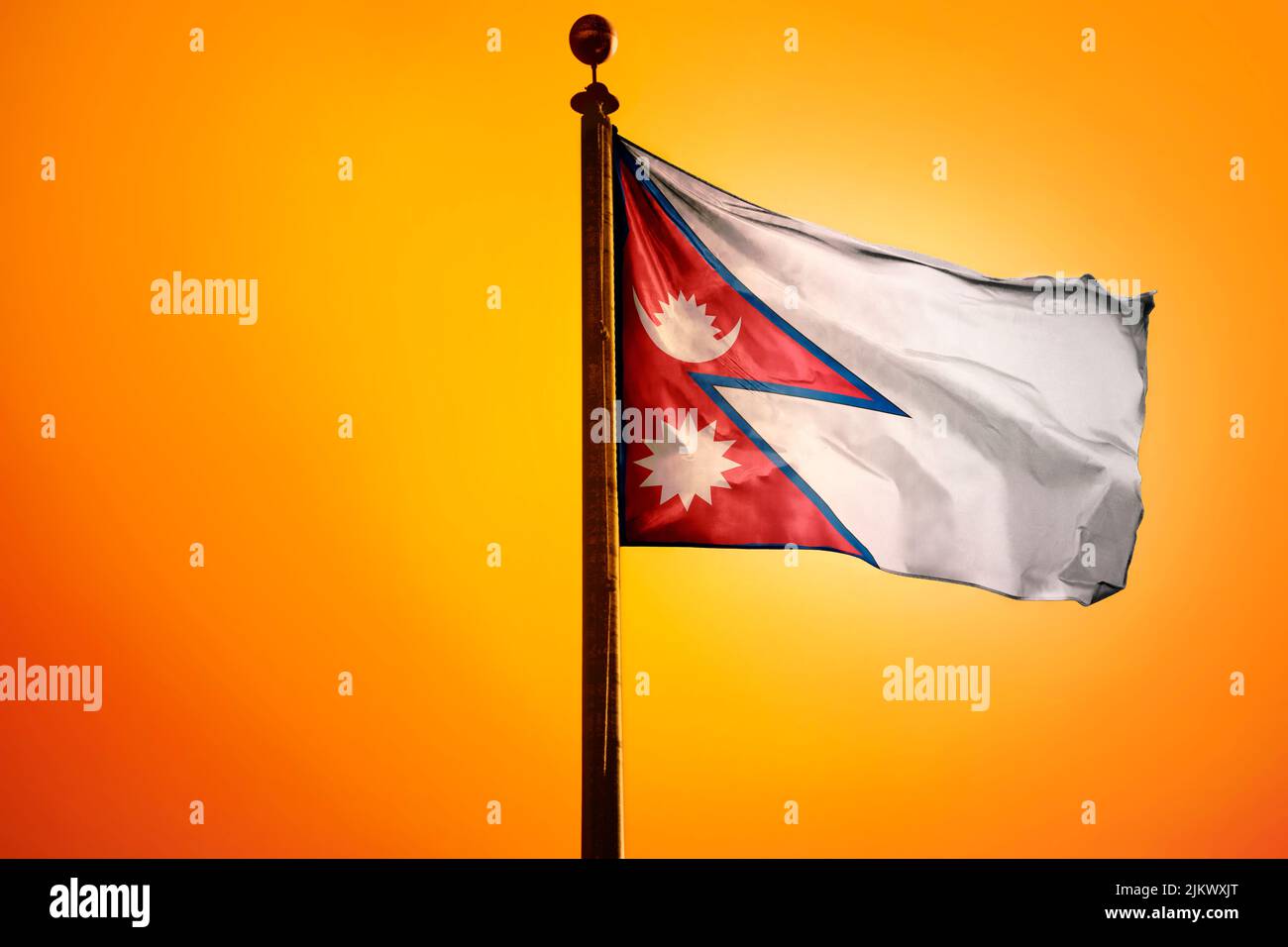 The national flag of Nepal on a flagpole isolated on an orange ...