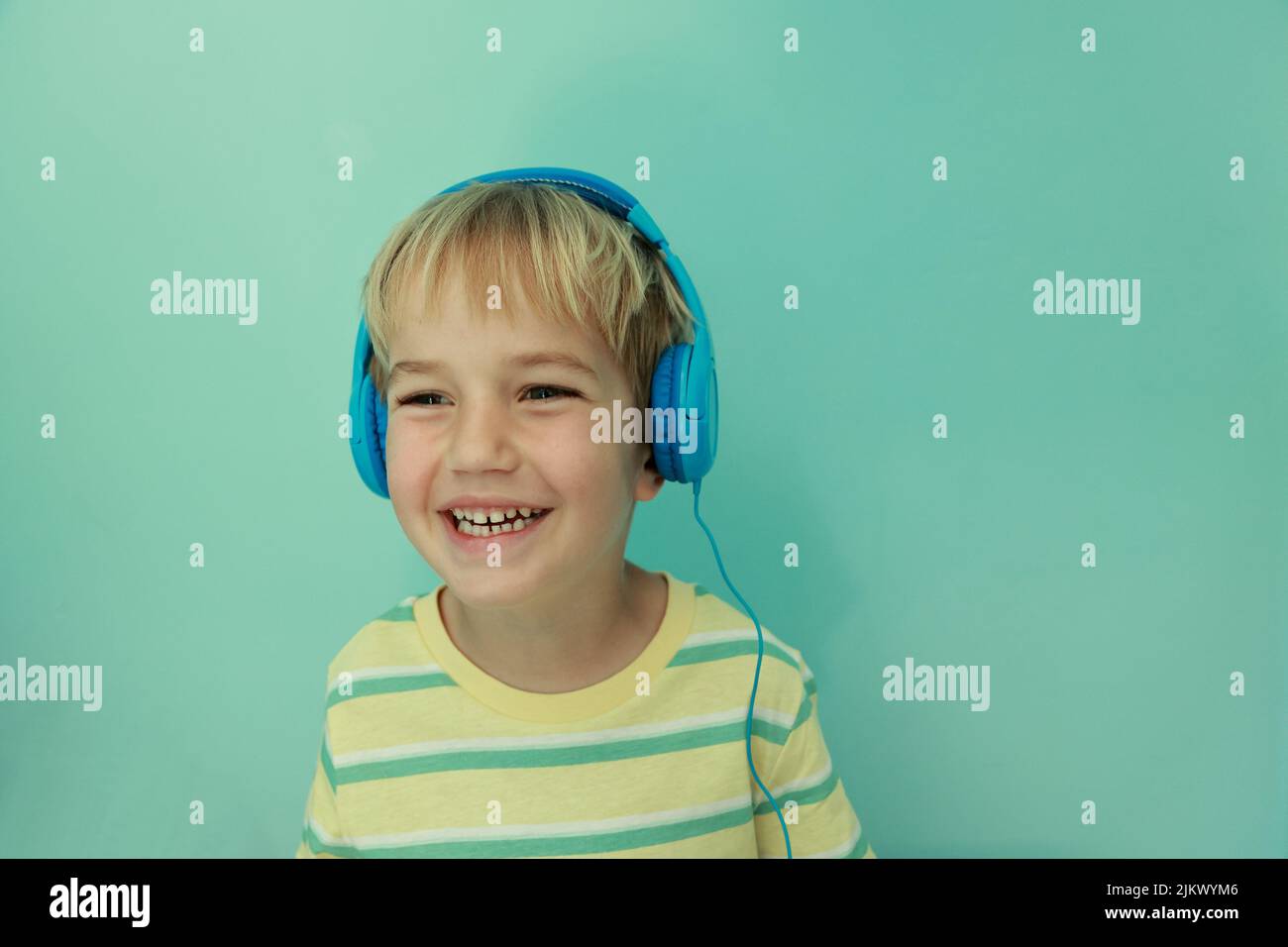 Happy small 5s kid boy wearing blue headphones, listening to music ...