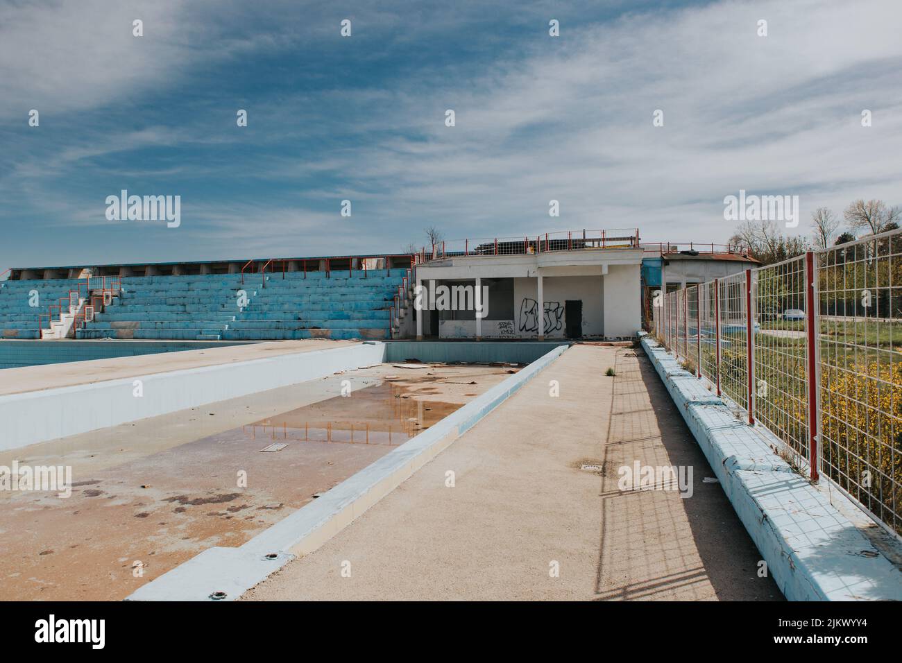 An old abandoned play yard under a blue cloudy sky in bright sunlight ...