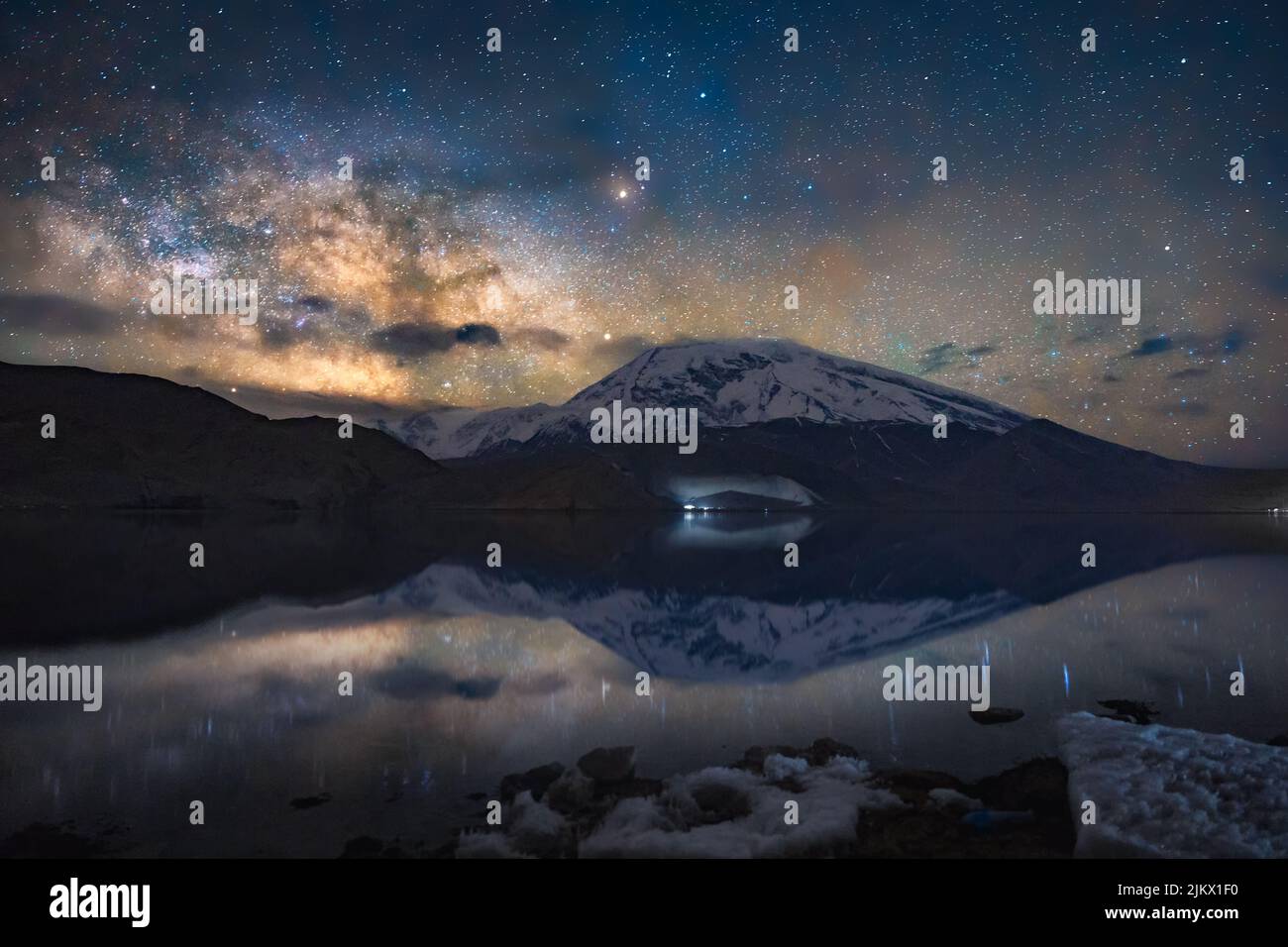 A beautiful view of a lake surrounded by hills under the night sky with ...