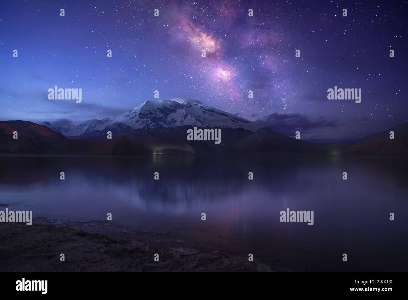 A beautiful view of a lake surrounded by hills under the night sky with ...