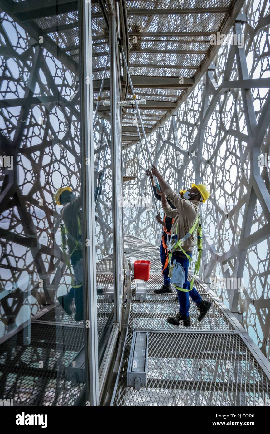 A vertical shot of men cleaning the windows of towers in Doha, Qatar ...