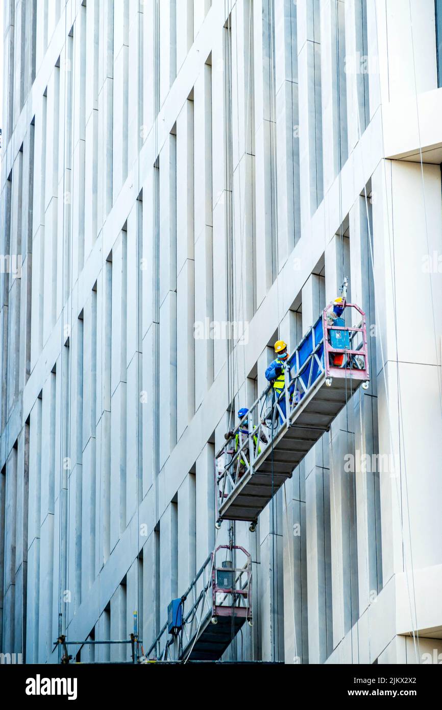 A vertical shot of men cleaning the windows of towers in Doha, Qatar ...