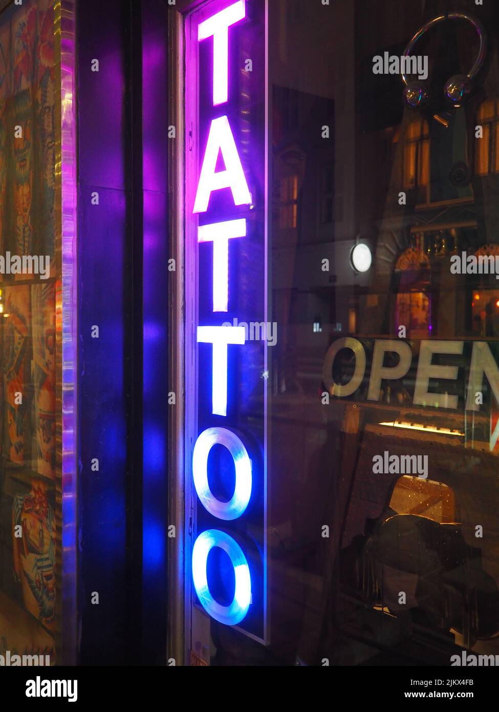 Tattoo sign at night behind a store window, open sign Stock Photo - Alamy