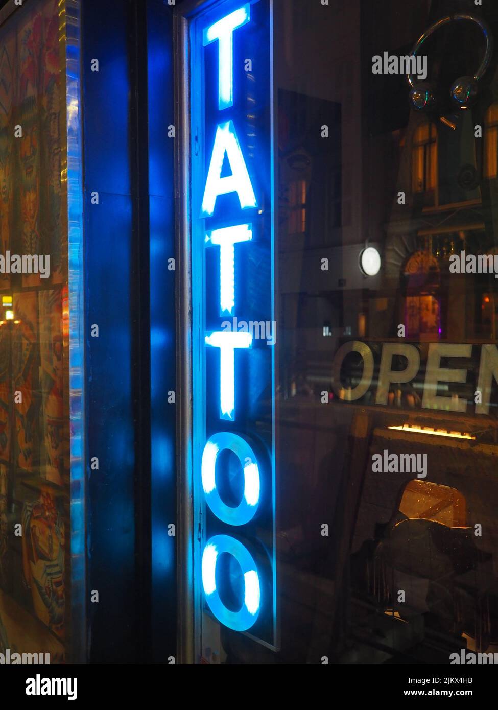 Tattoo sign at night behind a store window, open sign Stock Photo - Alamy
