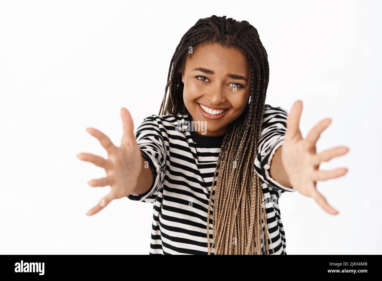 Portrait of smiling black girl stretching out hands to receive, take ...