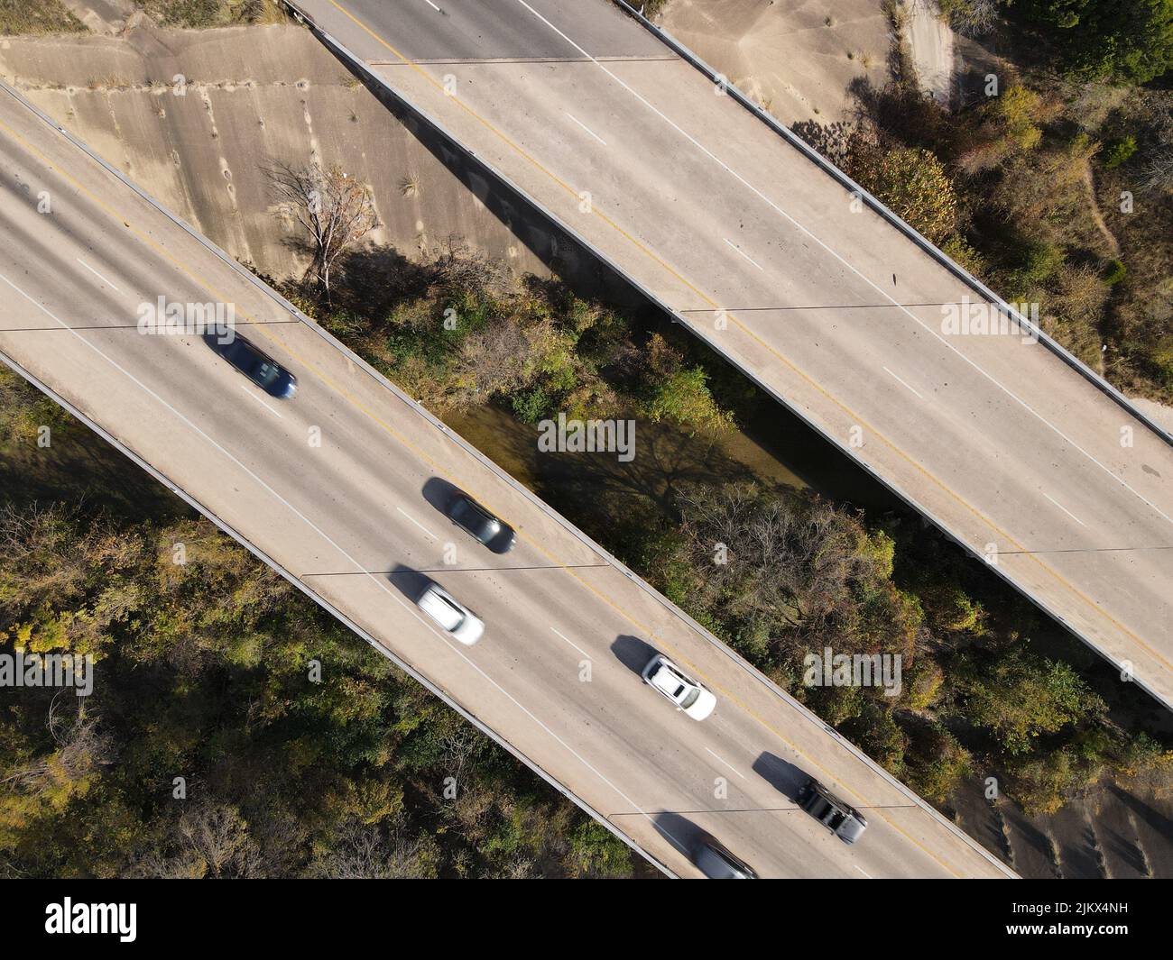 An aerial view of cars driving on a bridge above a river flowing ...