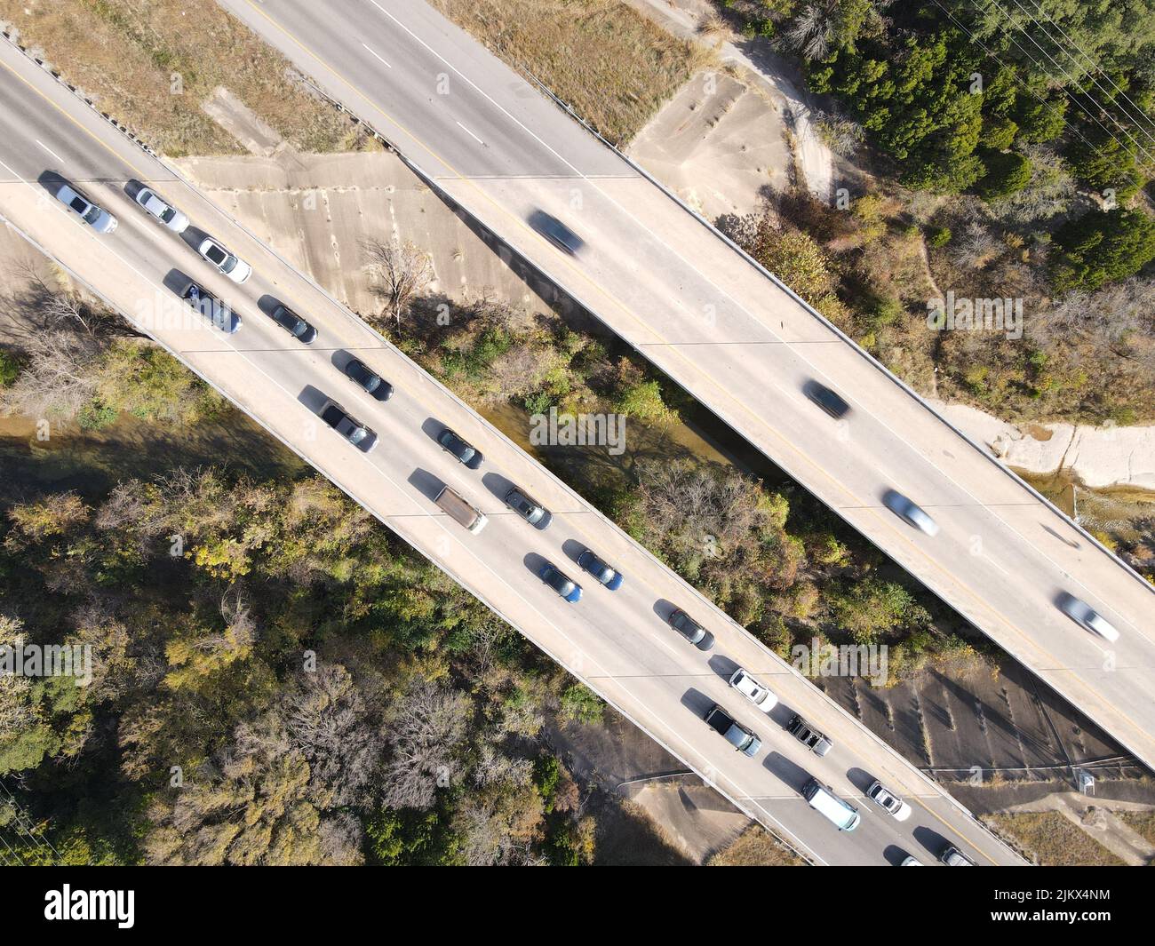 An aerial view of cars driving on a bridge above a river flowing ...