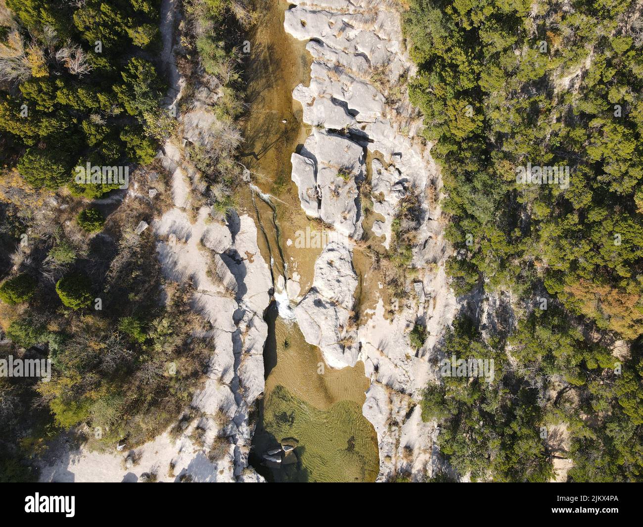 An aerial top view of a river flowing through its banks covered with ...
