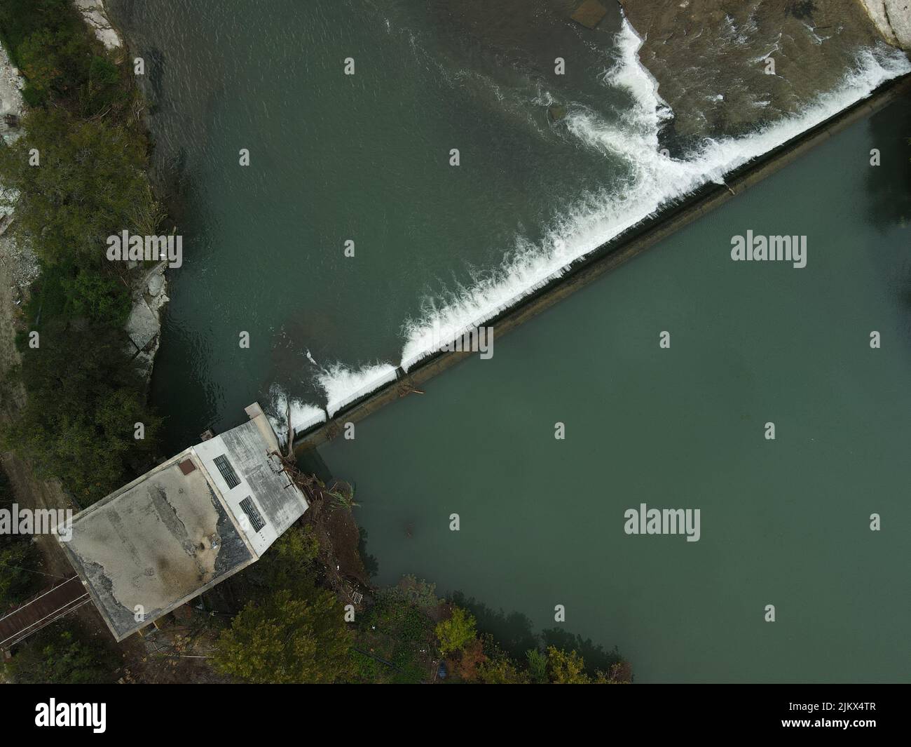 An aerial top view of a dam on a river flowing through its banks ...