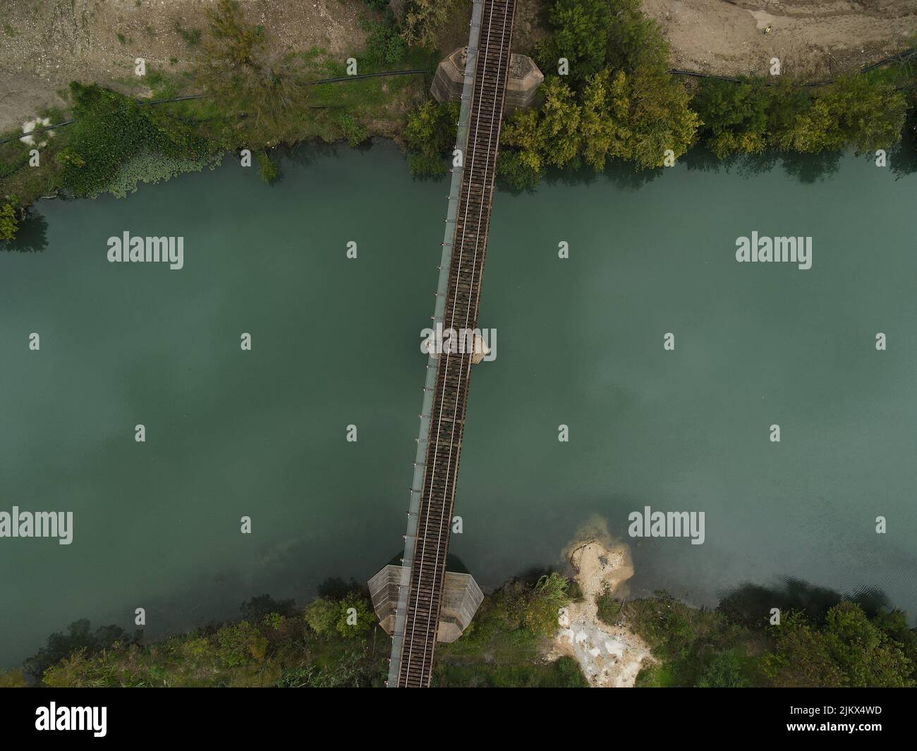 An aerial top view of a bridge above a river flowing through its banks ...