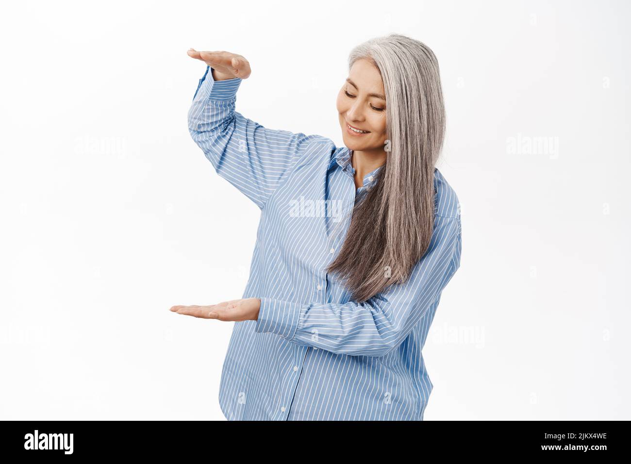 Holding big product. Smiling asian woman showing item in her hands ...