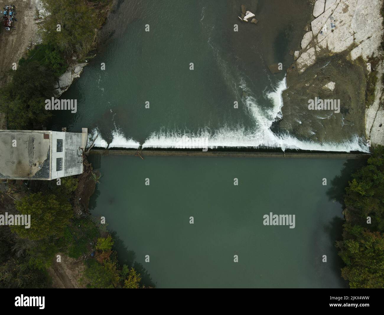 An aerial top view of a dam on a river flowing through its banks ...