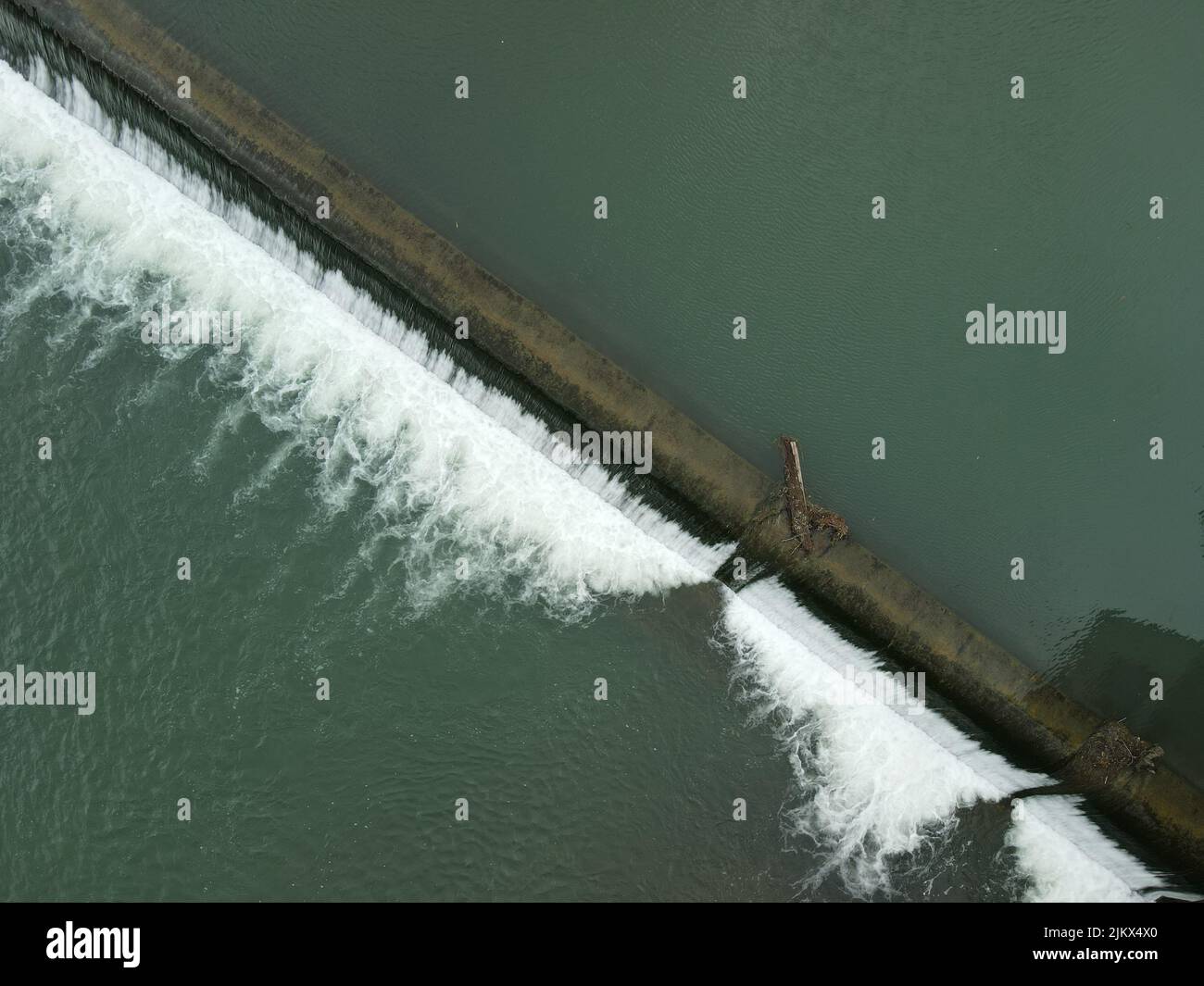 An aerial top view of a dam on a river flowing through its banks ...