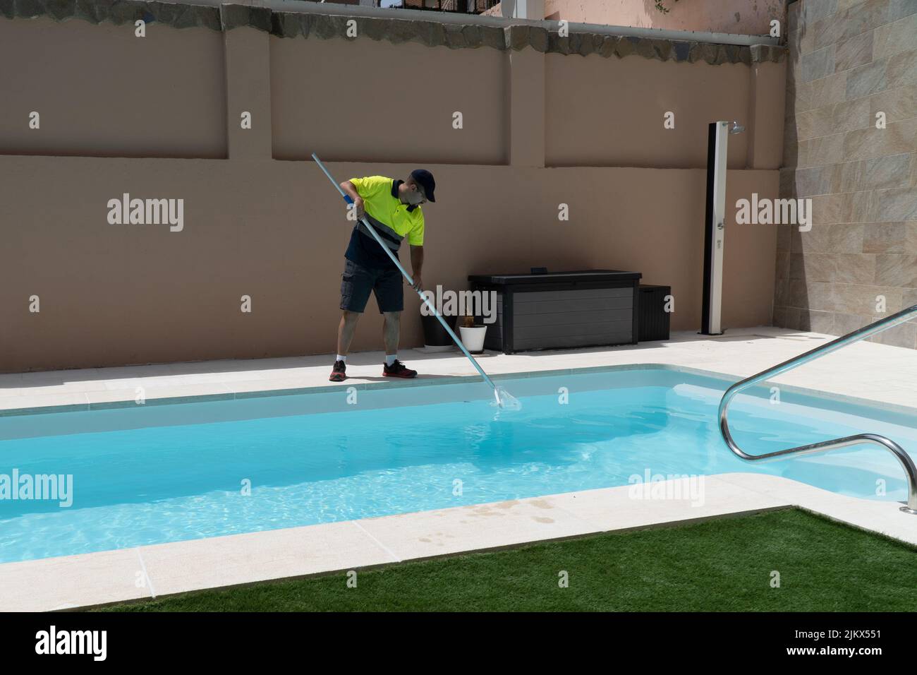 Operator cleaning a swimming pool with a butterfly trap, with ...