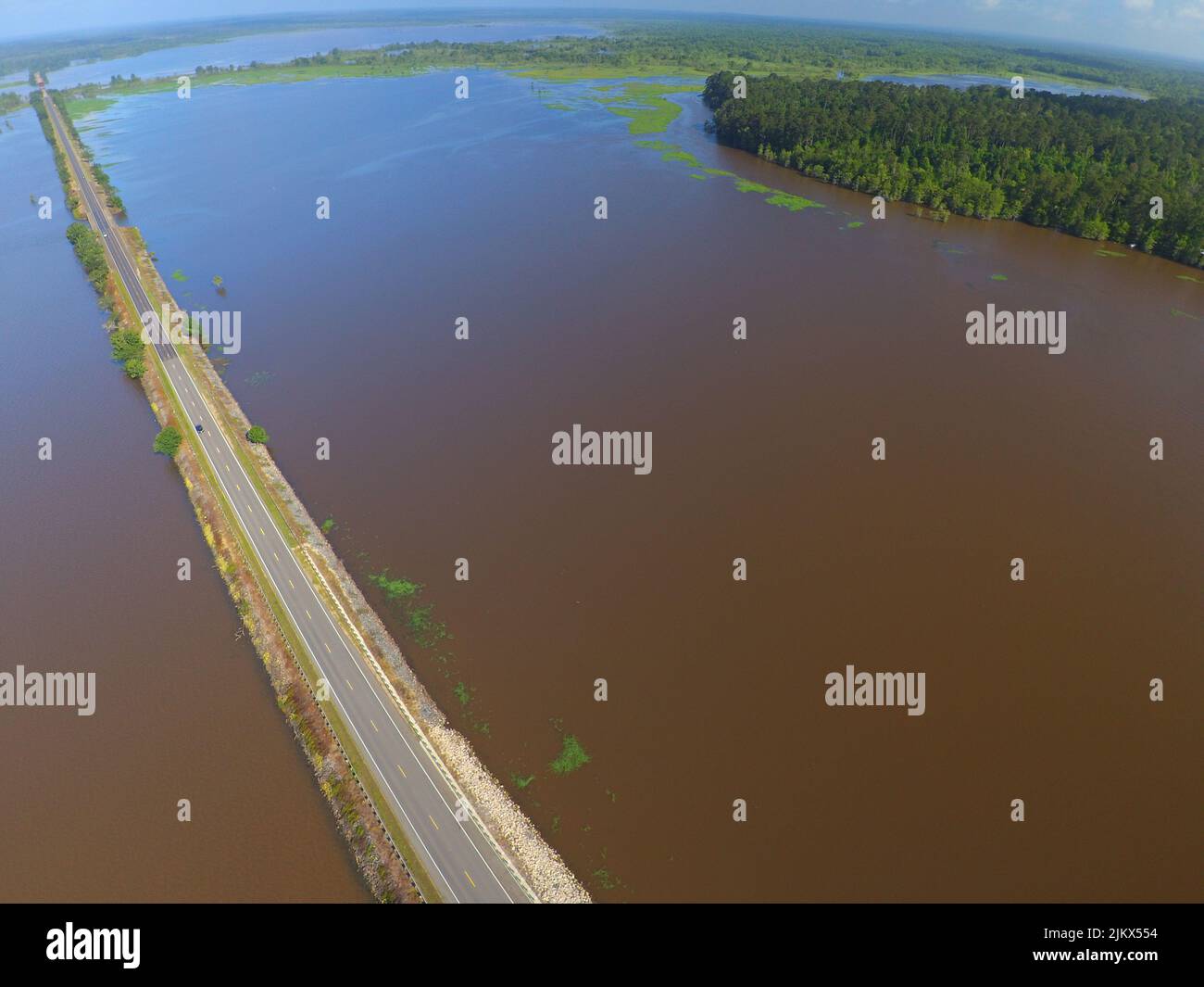 A bird's eye view of an asphalt road island surrounded by lakes washing ...