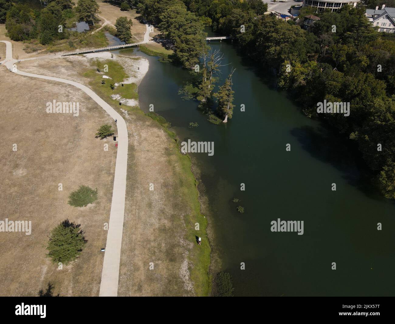 An aerial top view of a river flowing through its banks covered with ...