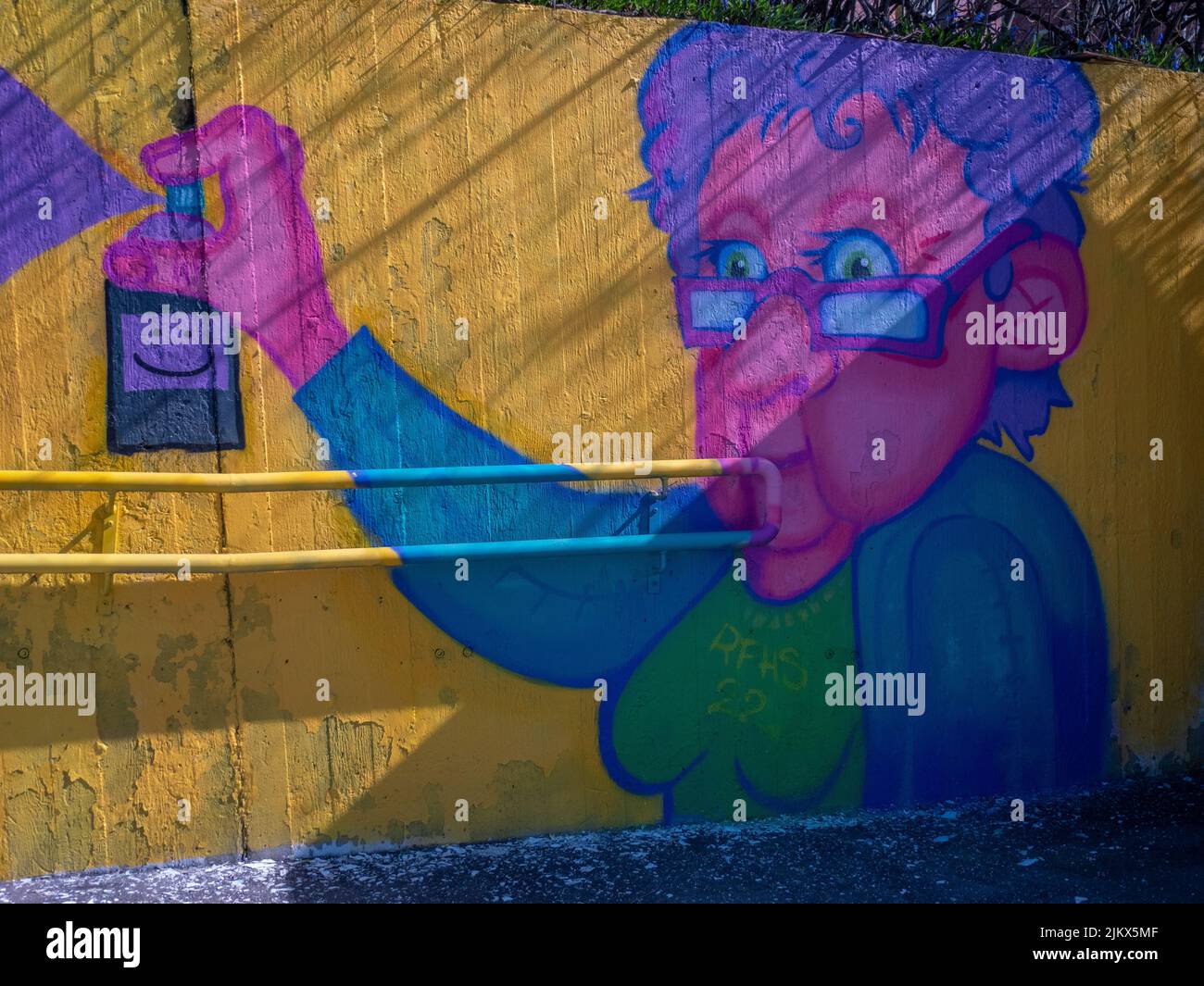 A closeup of colorful graffiti of an old woman with an aerosol spray ...