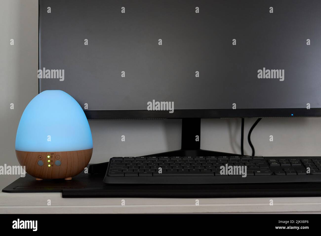 A closeup of a humidifier with blue light put near a computer Stock ...