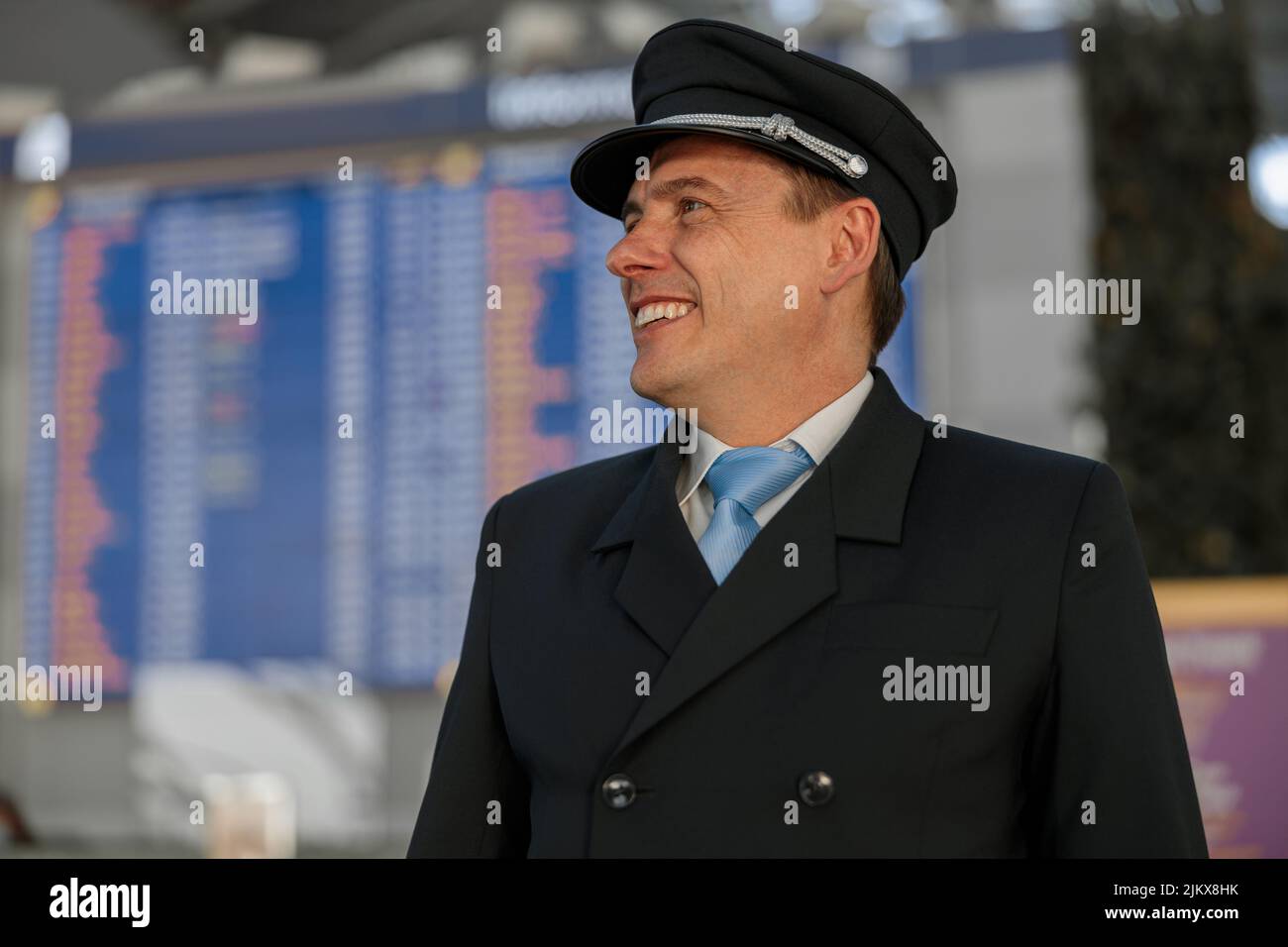 Happy adult pilot standing at the airport against the background of the ...